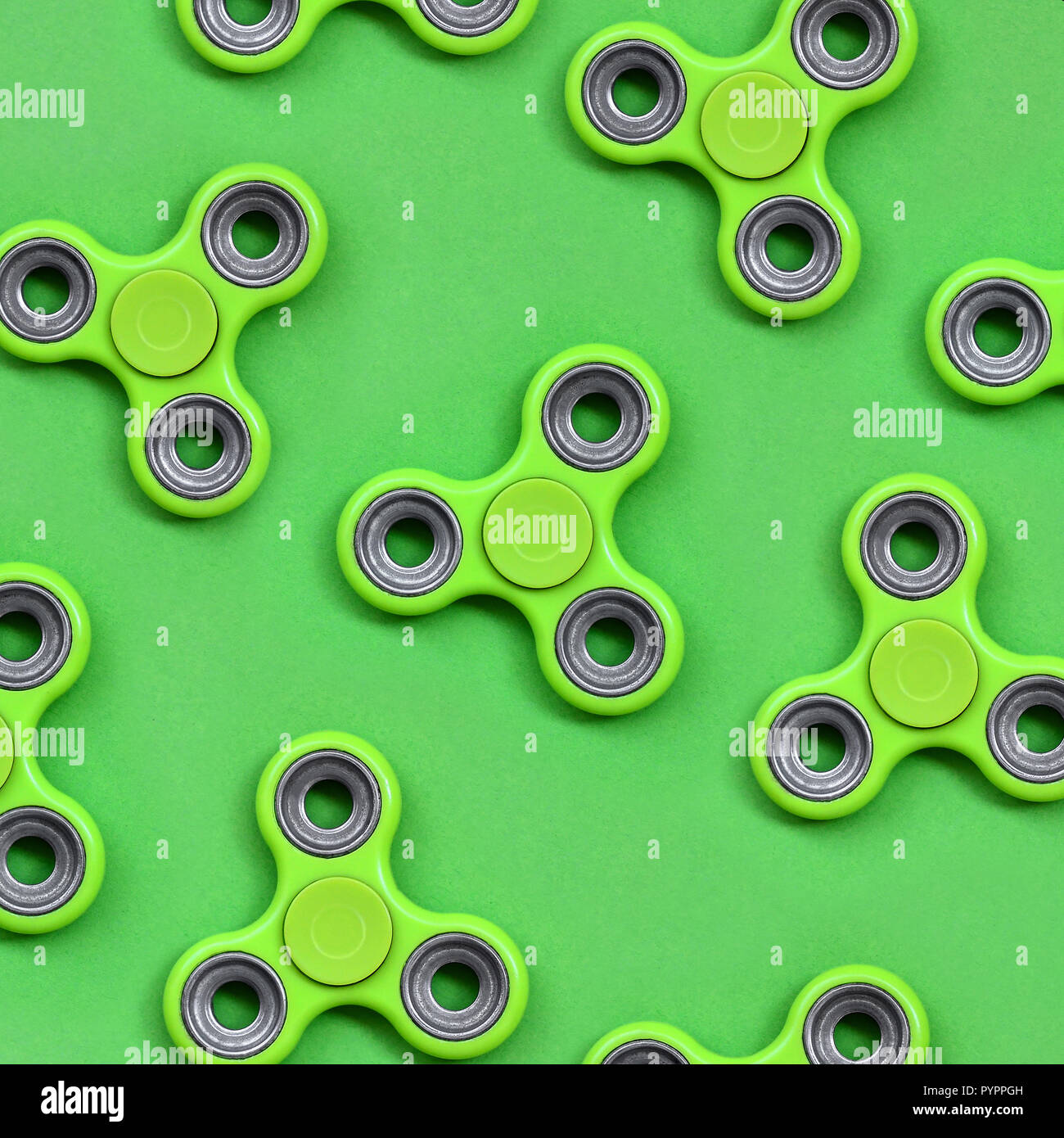 Many green fidget spinners lies on texture background of fashion pastel ...