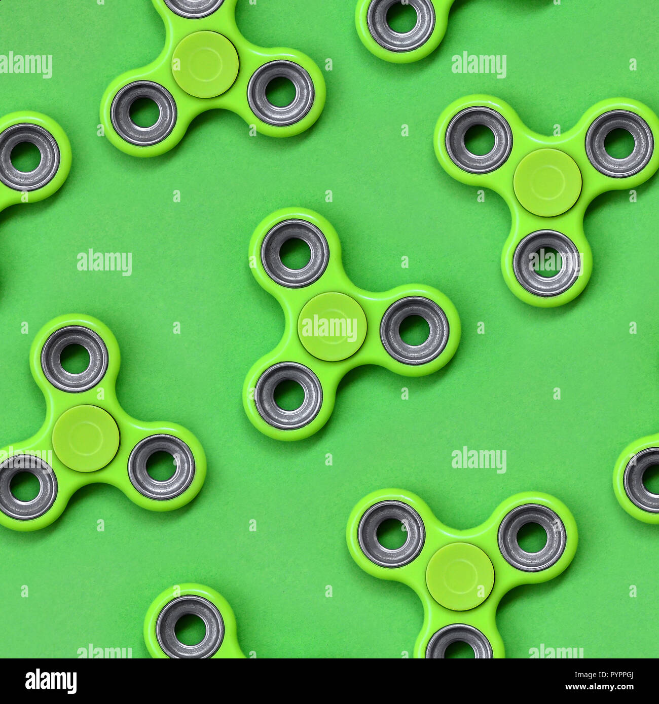Many green fidget spinners lies on texture background of fashion pastel ...
