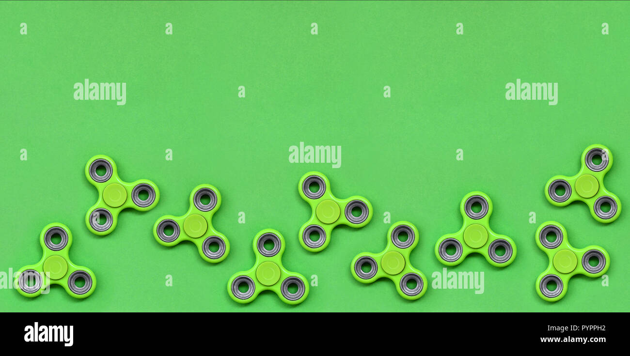 Many green fidget spinners lies on texture background of fashion pastel ...