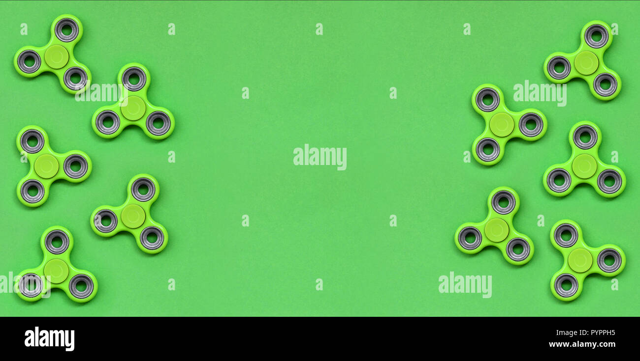 Many green fidget spinners lies on texture background of fashion pastel ...