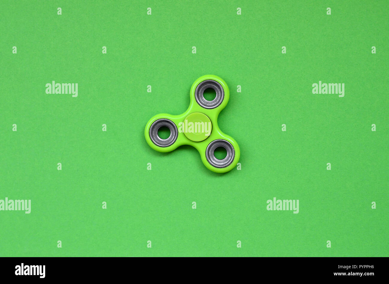 Green fidget spinner lies on texture background of fashion pastel green ...