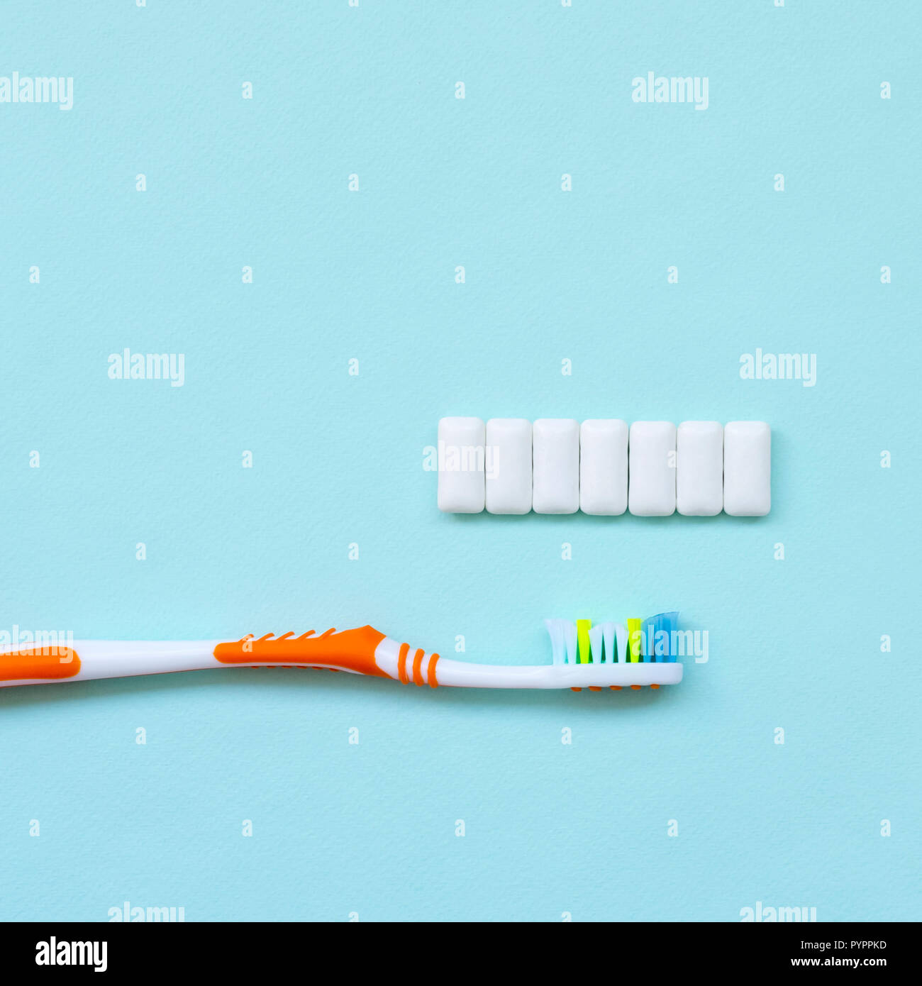 Toothbrush and chewing gums lie on a pastel blue background. Top view ...