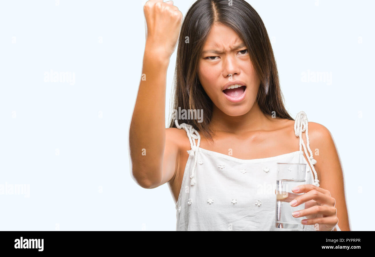 Young asian woman drinking glass of water over isolated background ...