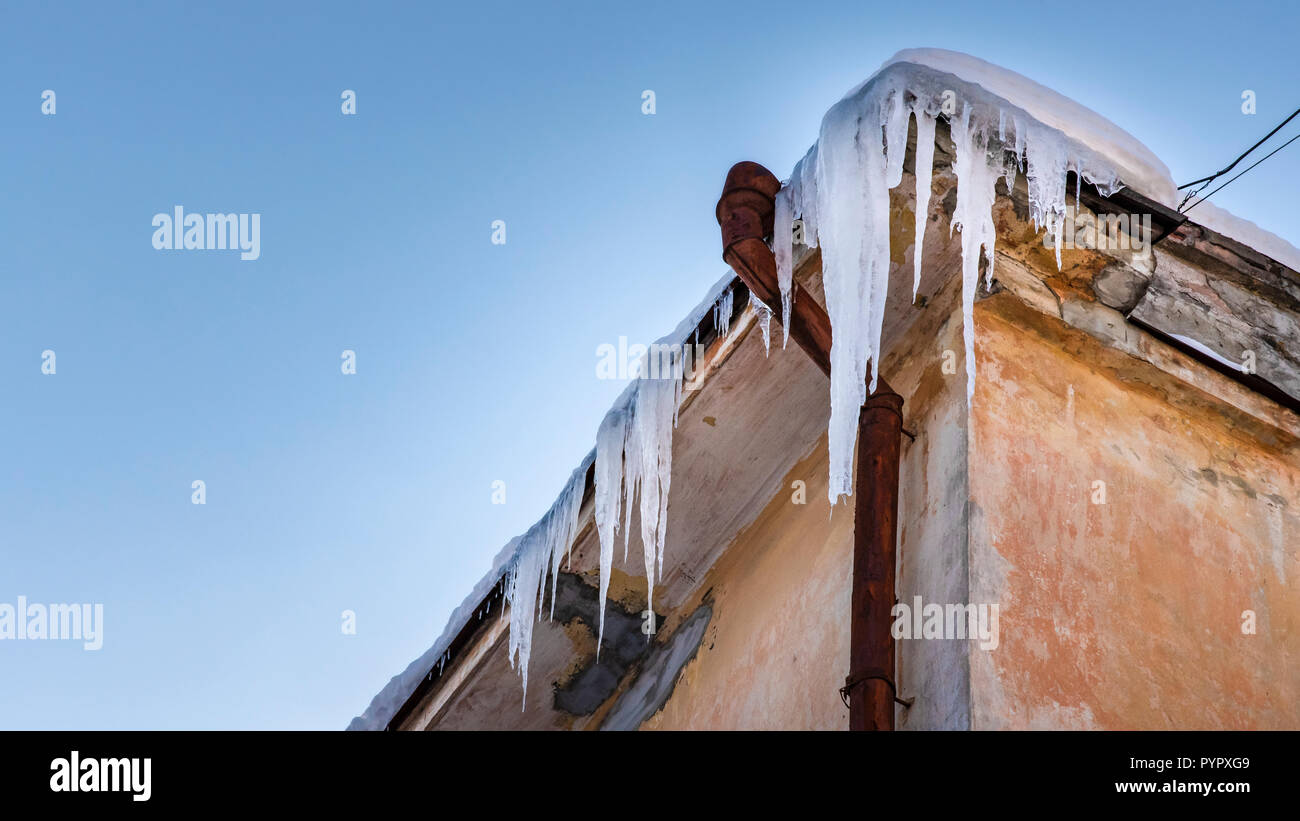 Icicles hang from roof of building. Danger for passers, threat of death ...