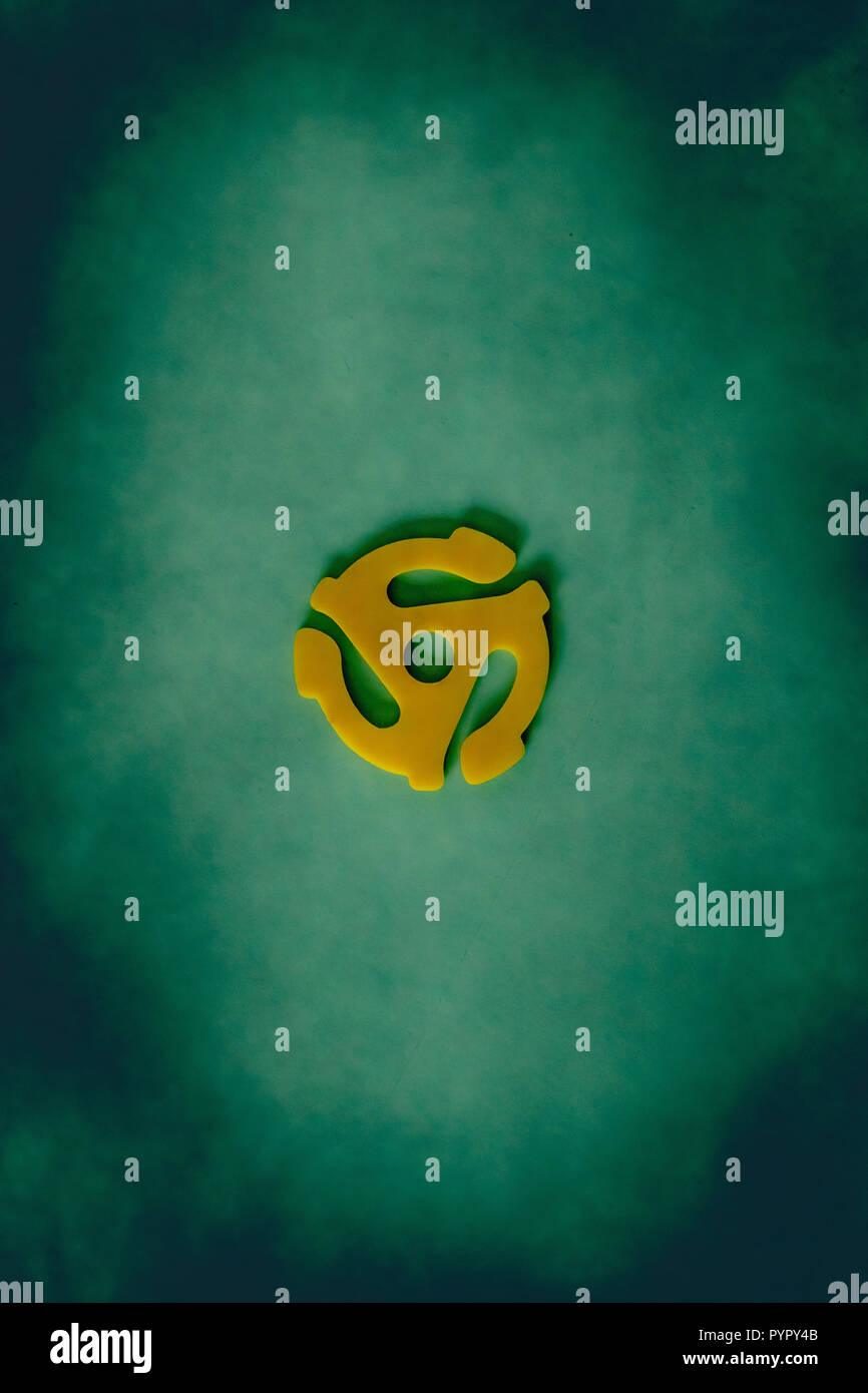 A vintage yellow record adapter to play a 45 speed record on a 33 ...