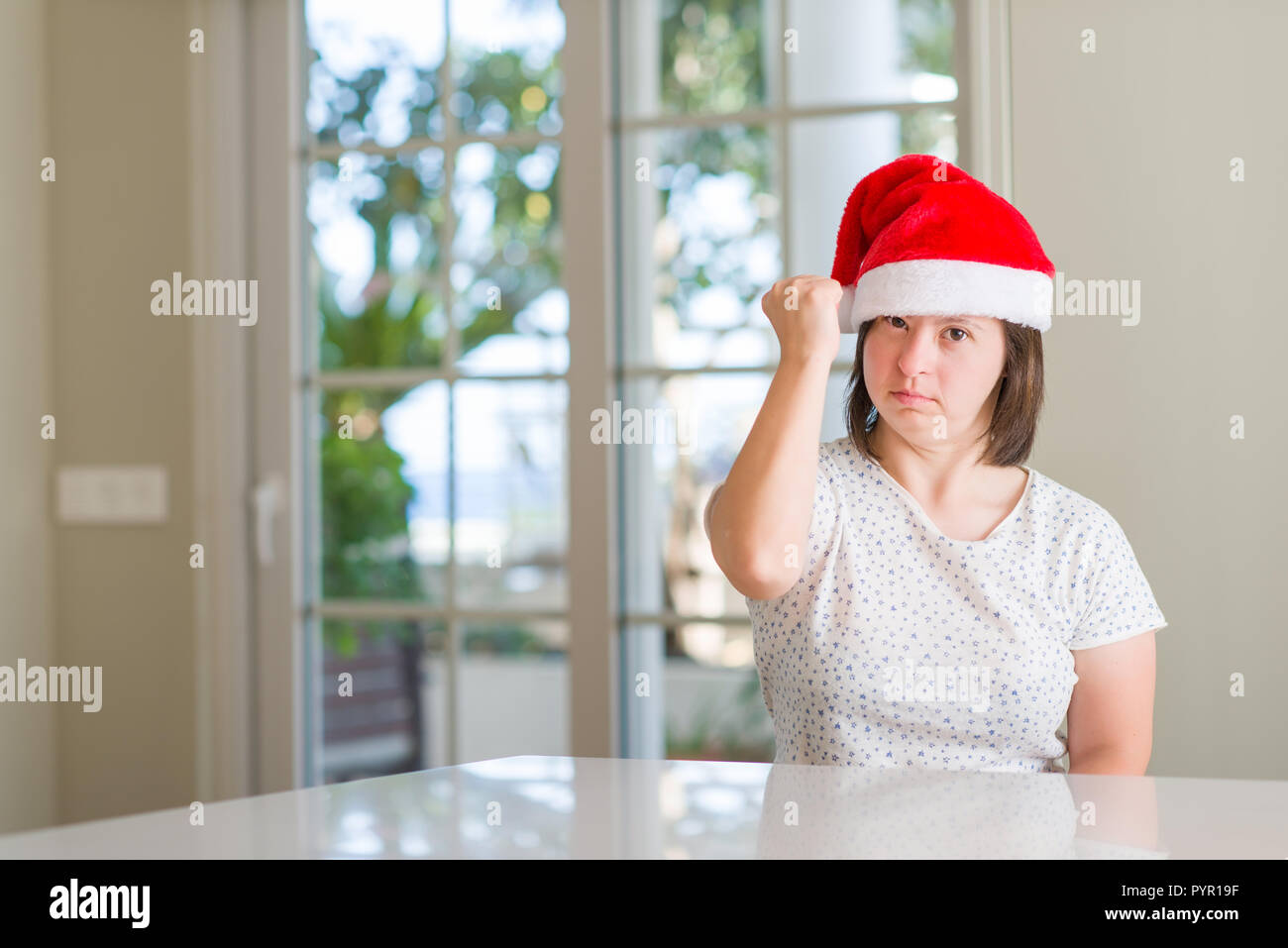 Down syndrome woman at home wearing christmas hat annoyed and ...