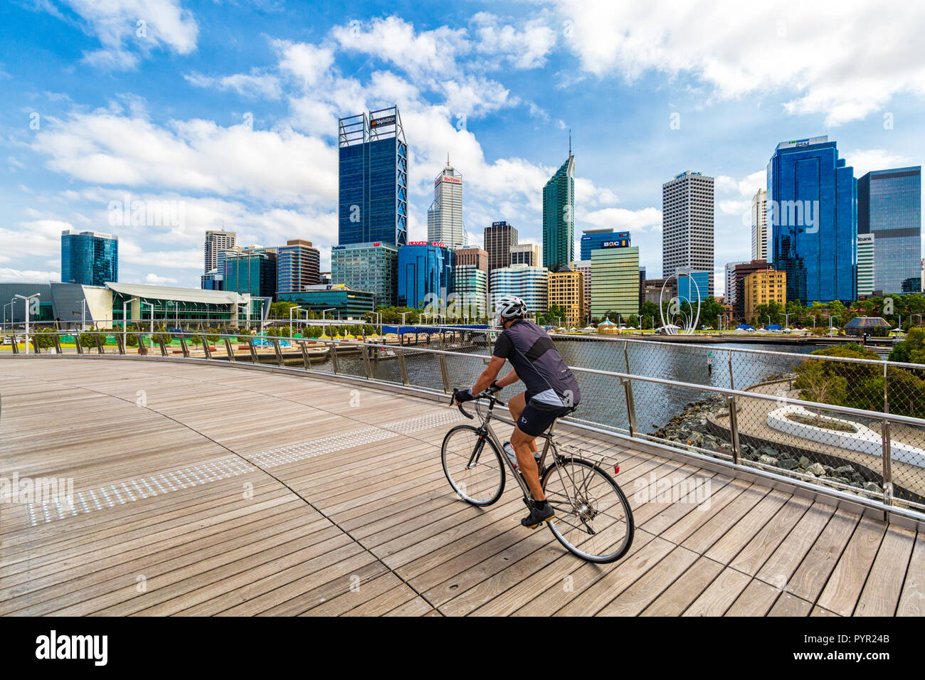A man cycling over Elizabeth Quay Bridge with a view of Perth city in ...