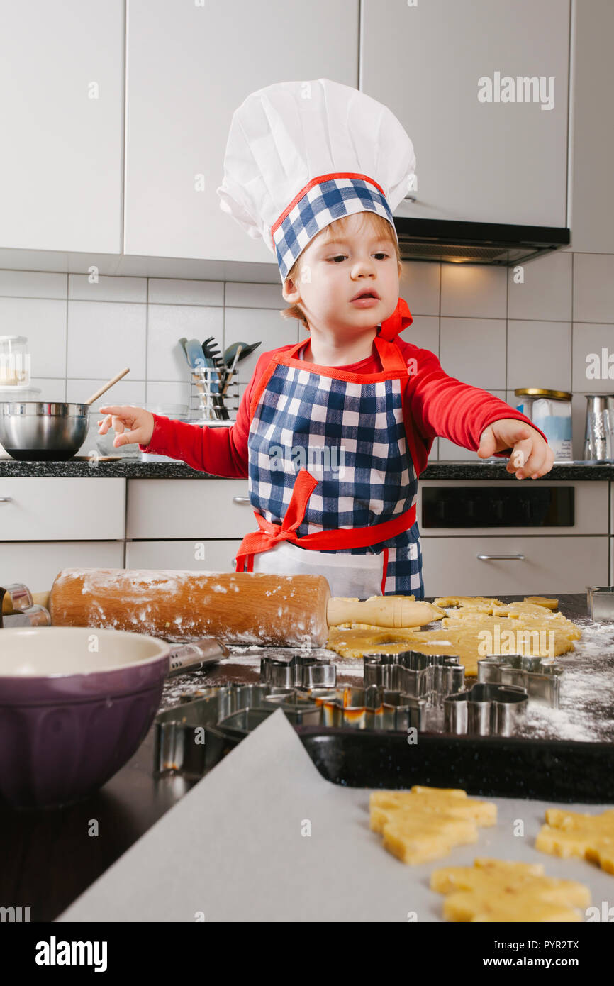 Photo of an adorable boy in a chef hat and apron making cookies in the ...