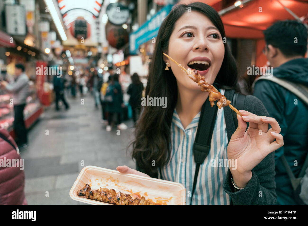 joyful woman experience local japanese culture eating tasty yakitori ...