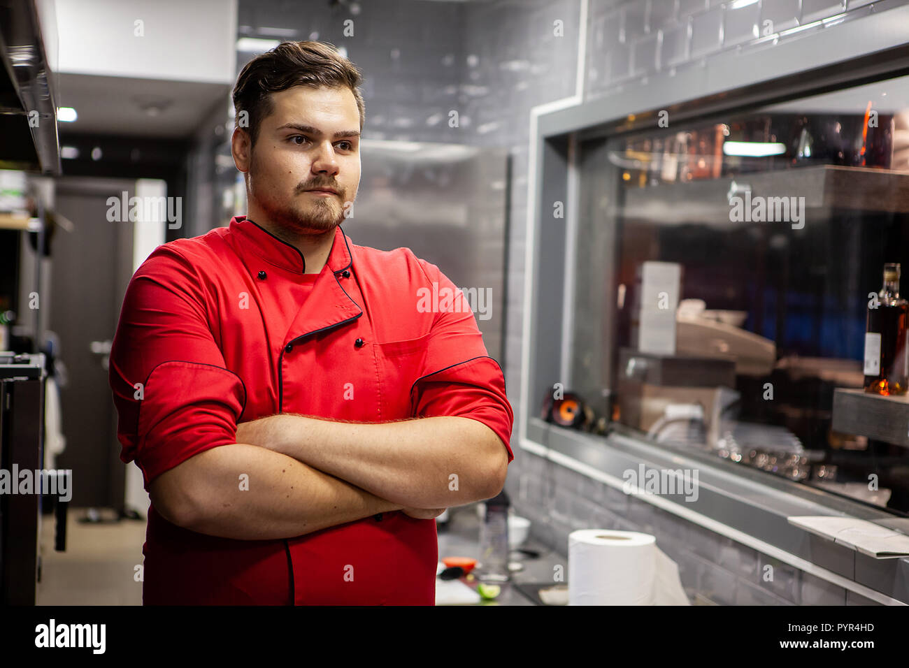 Portrait of male cook chef in kitchen in a restaurant with red clothes ...
