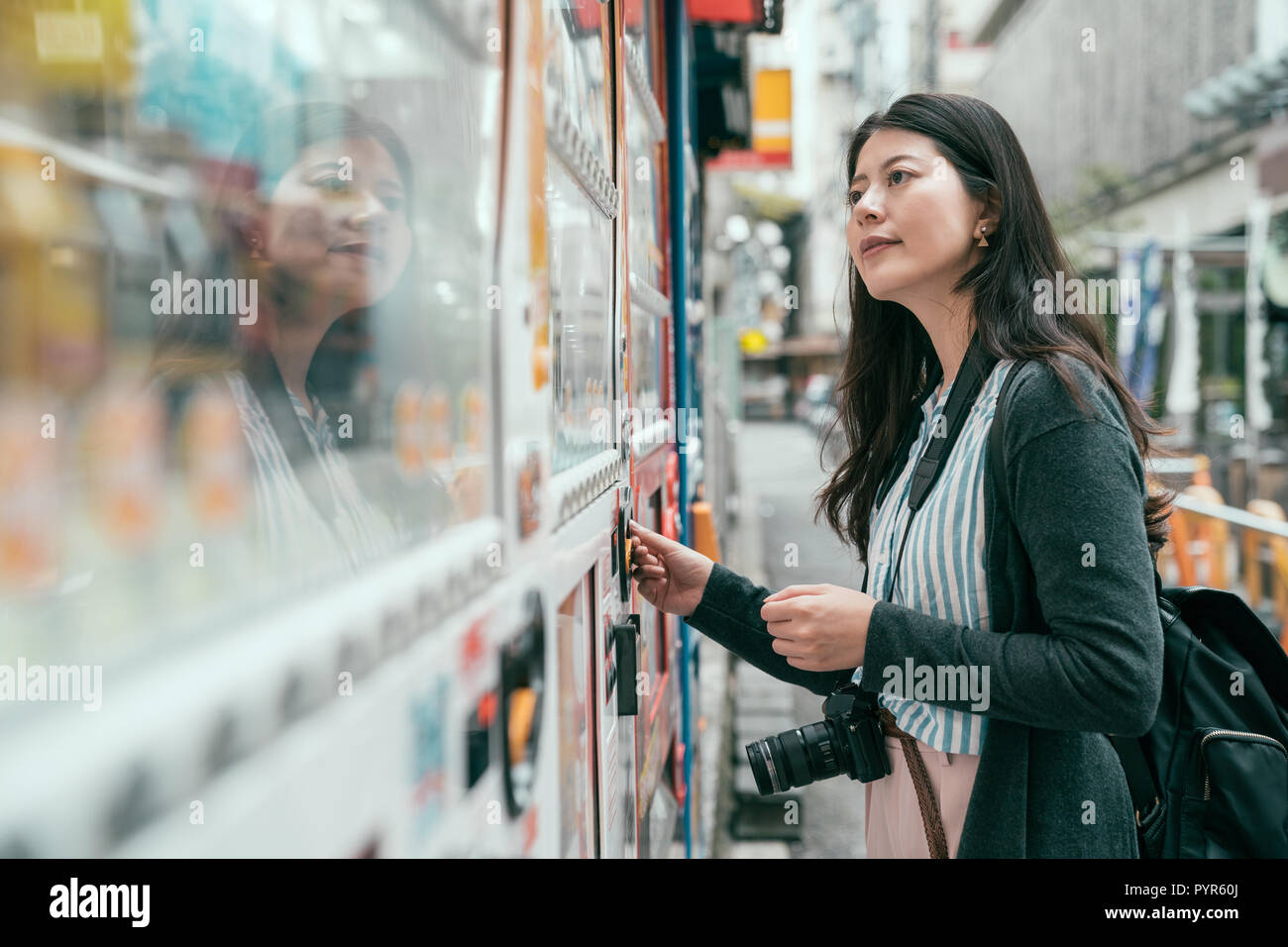 Japan vending machine. Young female tourist choosing a snack or drink ...