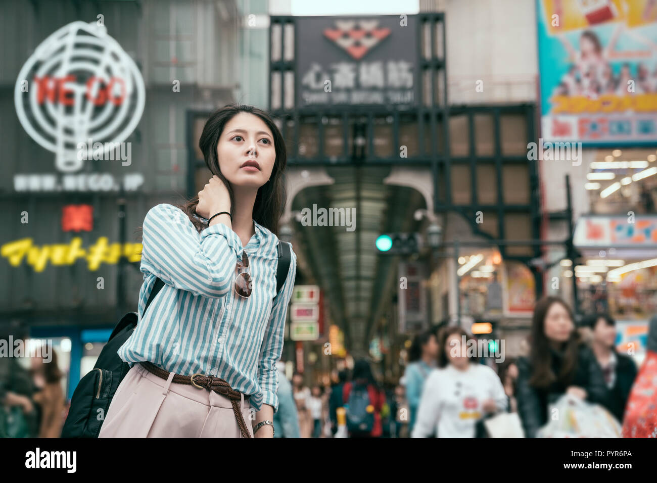 young traveler standing in front of the shinsaibashi. busy street crowd ...