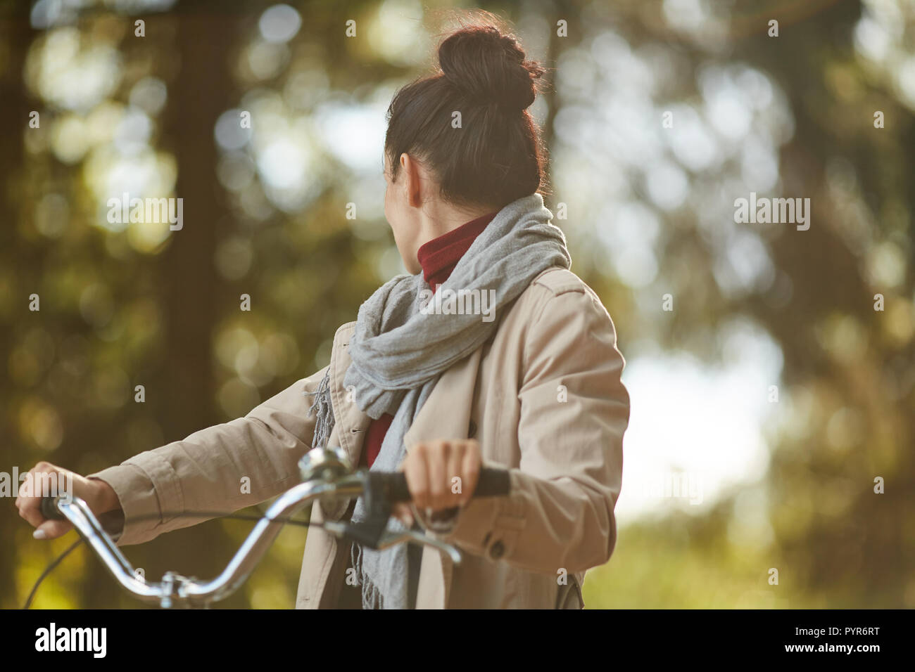 Woman cyclist looking around forest Stock Photo - Alamy