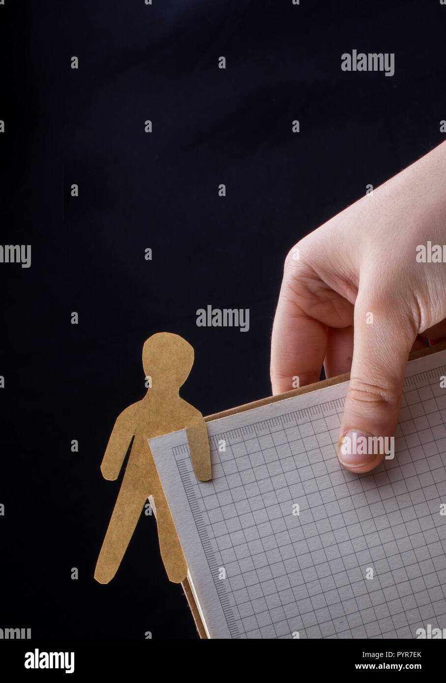Man shape cut out of paper in notebbok in hand Stock Photo - Alamy