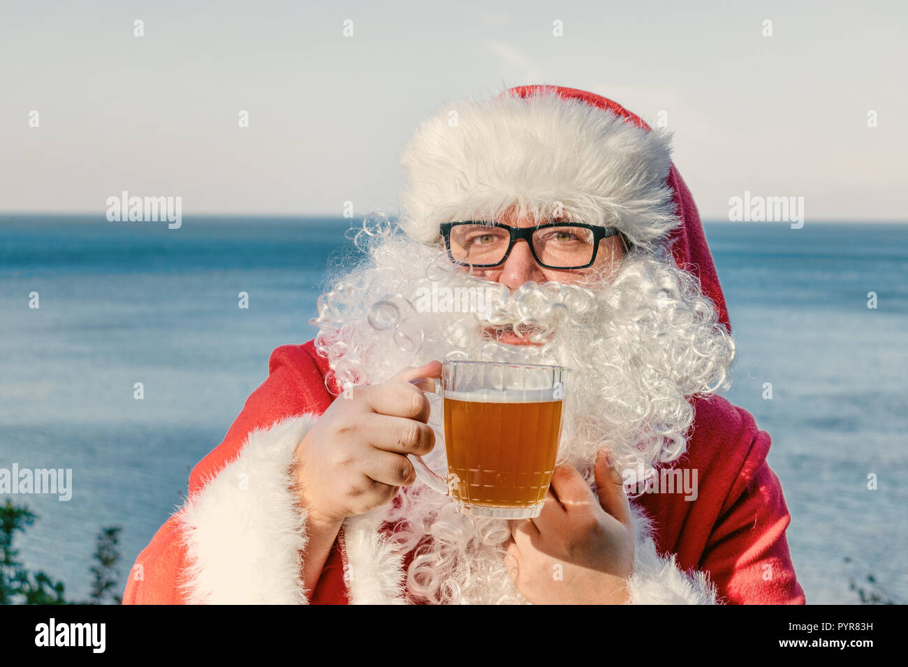 Fat man dressed as Santa drinking beer on the ocean Stock Photo - Alamy