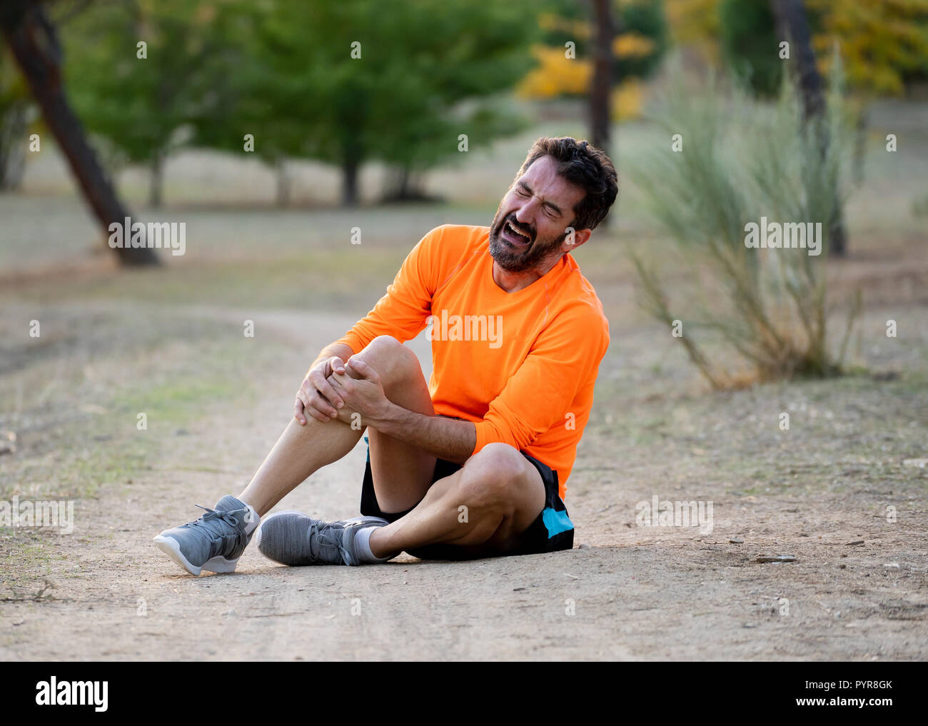Young fit man holding knee with his hands in pain after suffering ...