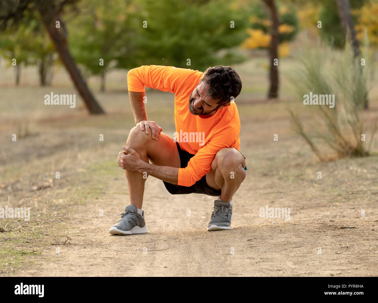 Young fit man holding knee with his hands in pain after suffering ...