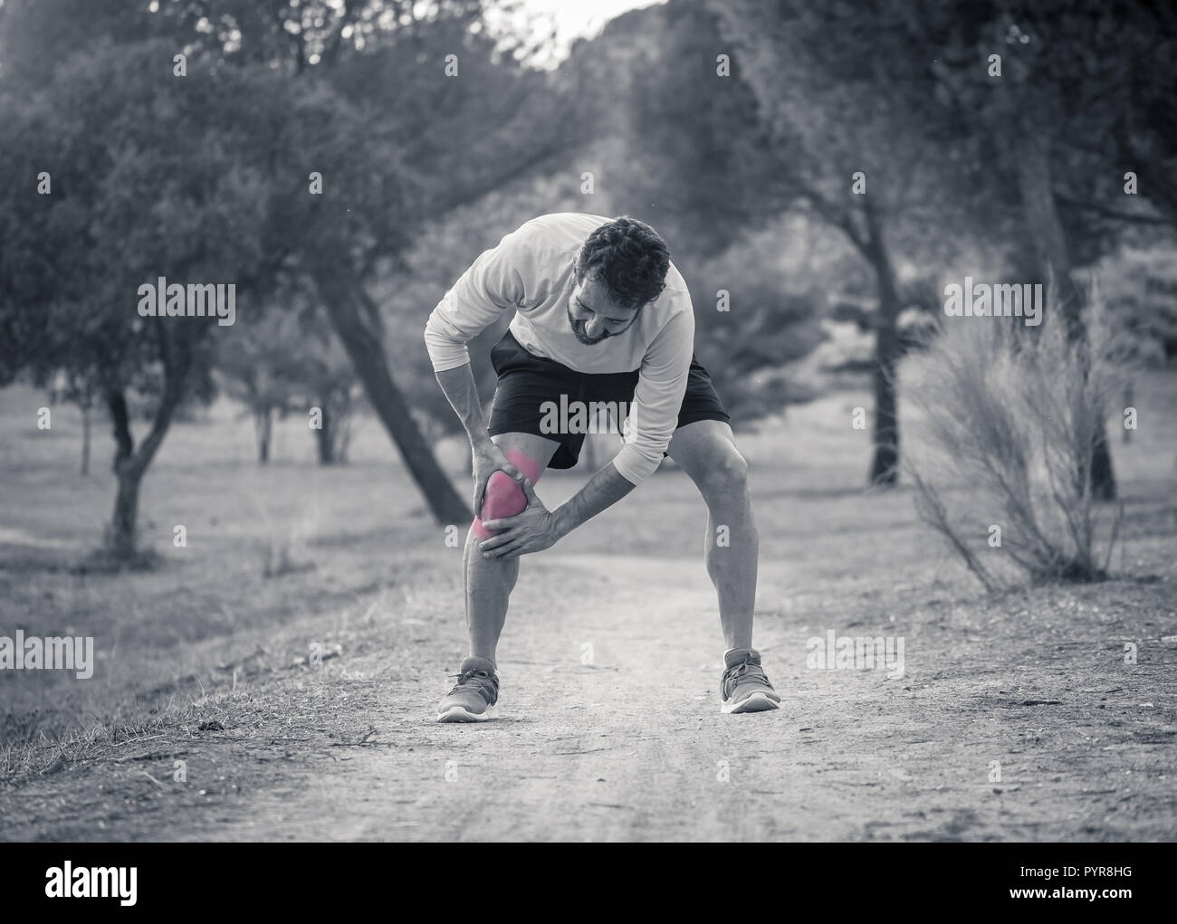 Young fit man holding knee with his hands in pain after suffering ...