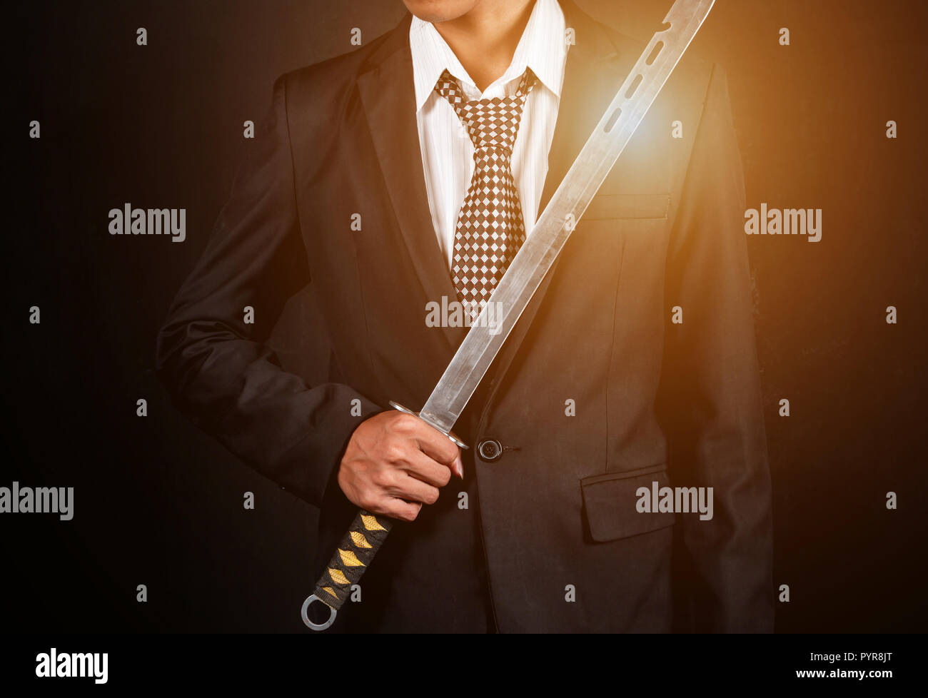The right hand of a businessman holding a sword on a dark background ...