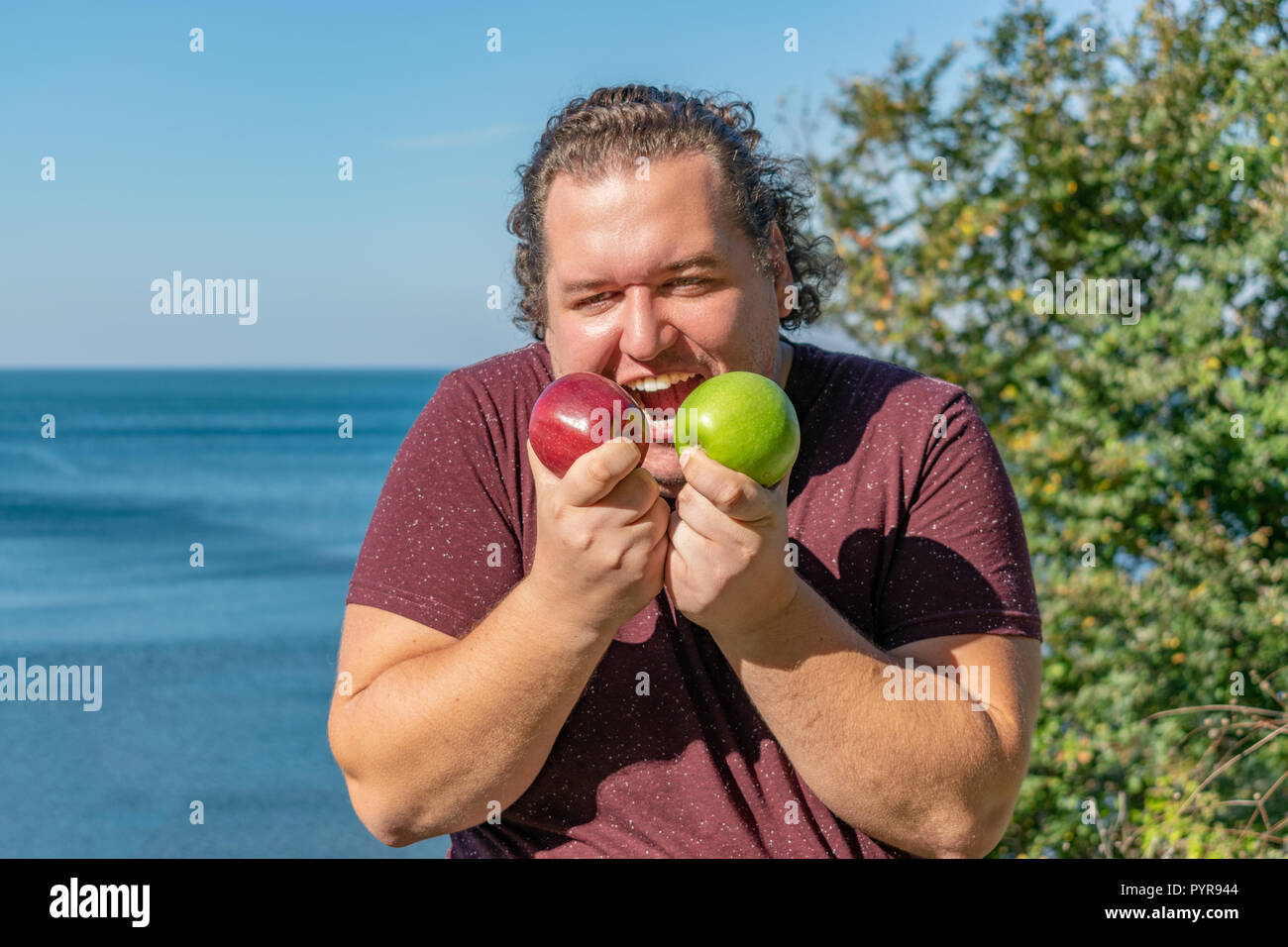 Funny fat man on the ocean eating fruits Stock Photo - Alamy