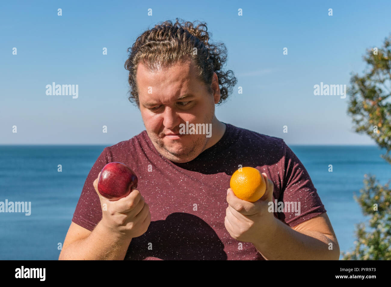 Funny fat man on the ocean eating fruits Stock Photo - Alamy