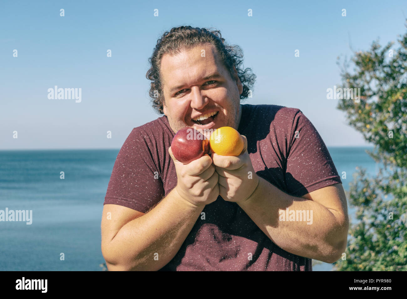 Funny fat man on the ocean eating fruits Stock Photo - Alamy