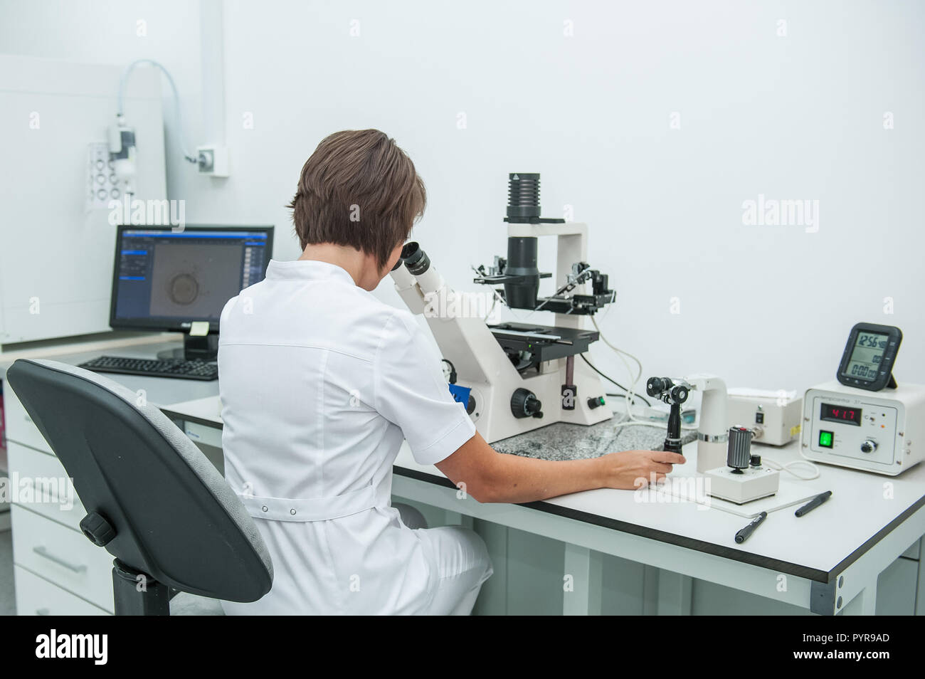 Young woman medical researcher looking through microscop slide in the ...