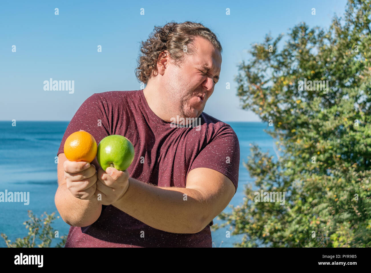 Funny fat man on the ocean eating fruits Stock Photo - Alamy