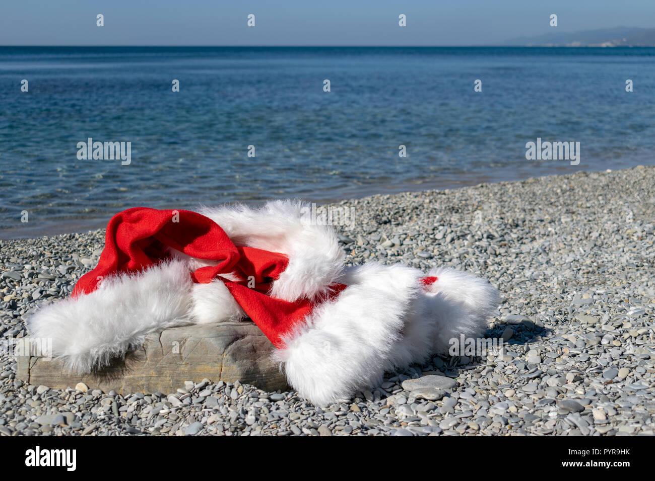 Santa Claus clothing and hat lies on a large stone on the seashore ...