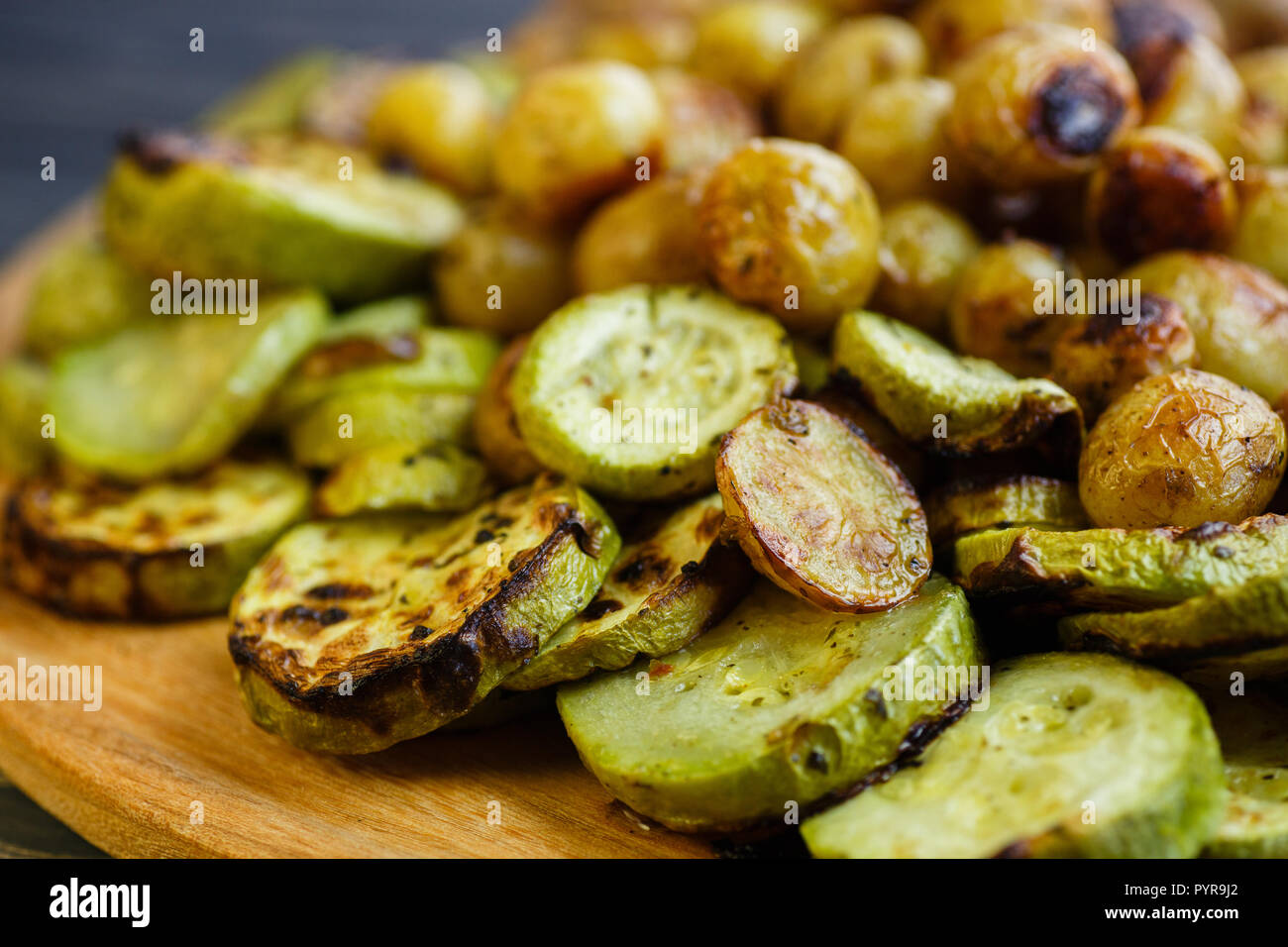 Grilled vegetables and chicken wings on the wooden plate on the black ...
