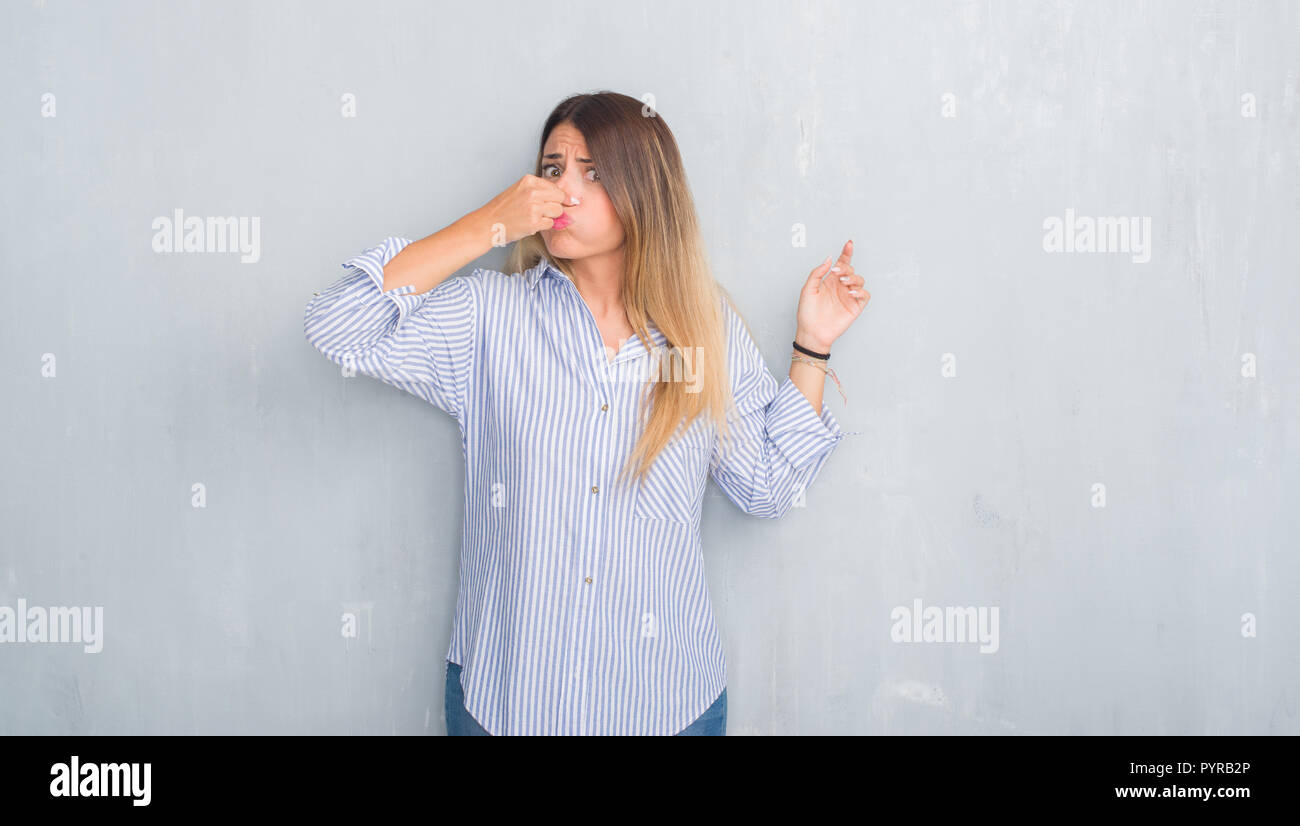 Young adult woman over grey grunge wall wearing fashion business outfit ...
