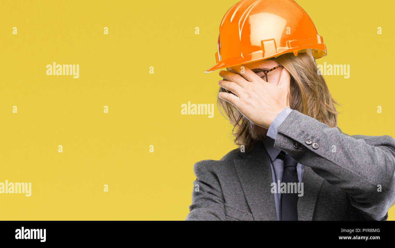 Young handsome architec man with long hair wearing safety helmet over ...