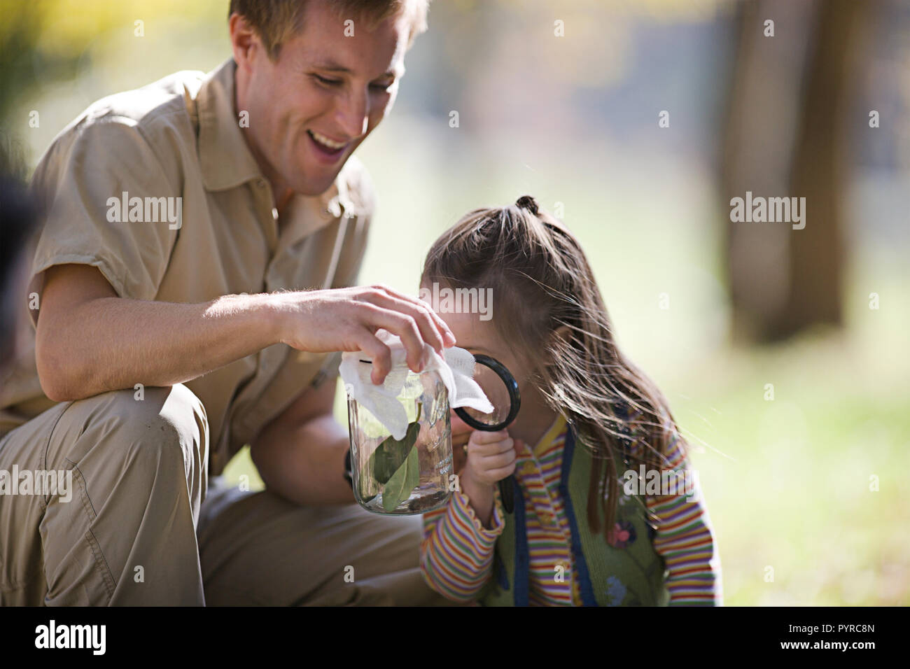 Ranger holding bugs in a jar for little girl to examine with a ...