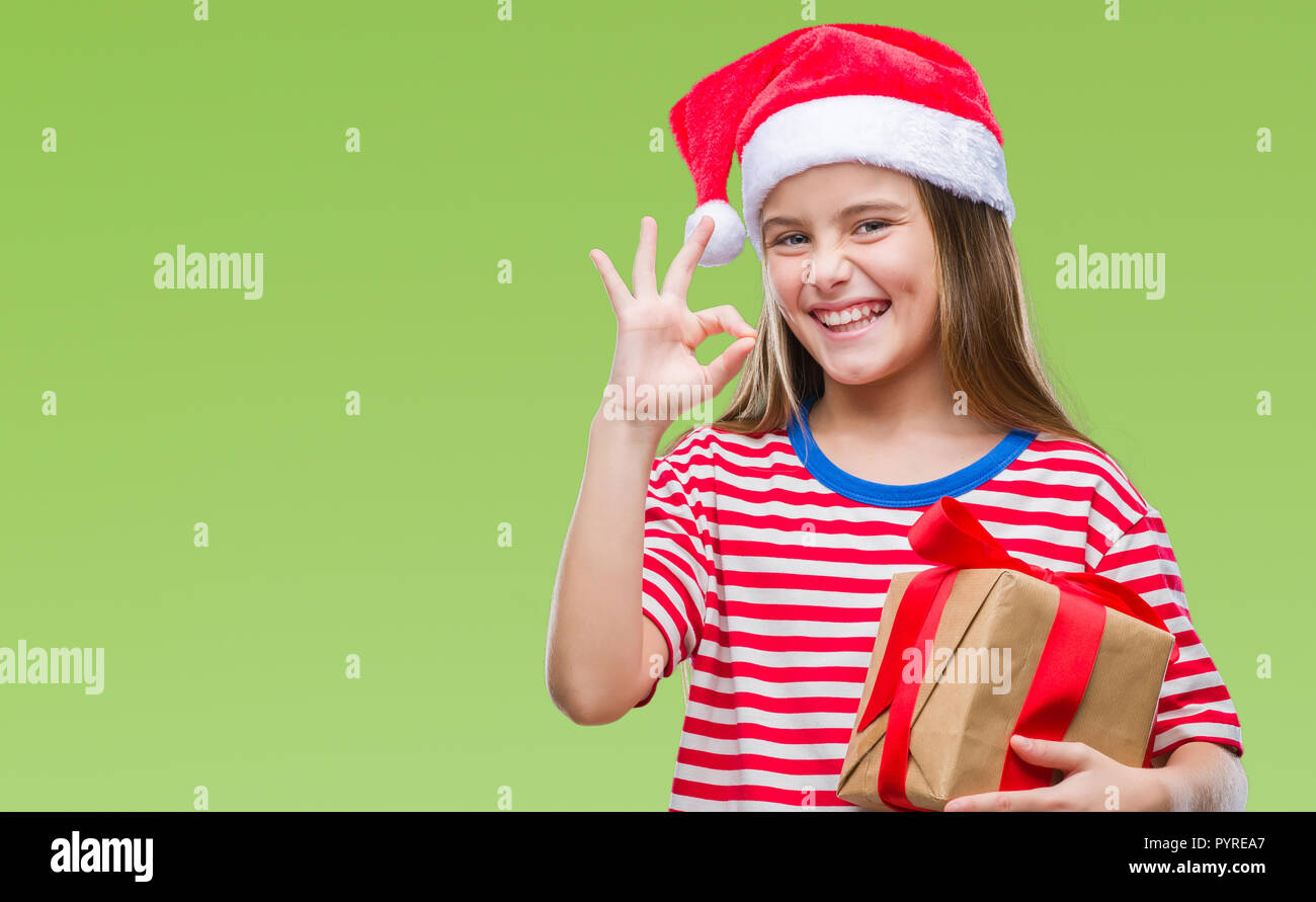 Young beautiful girl wearing christmas hat and holding gift over ...