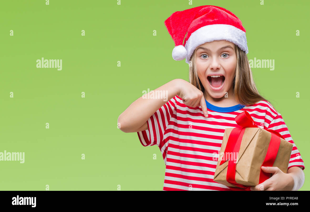 Young beautiful girl wearing christmas hat and holding gift over ...