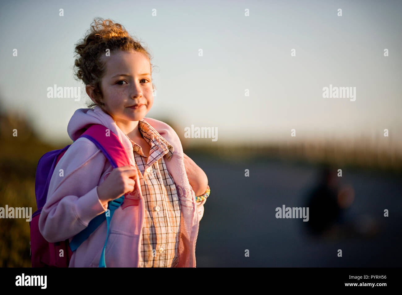 Portrait of a young girl standing with a backpack outside Stock Photo ...