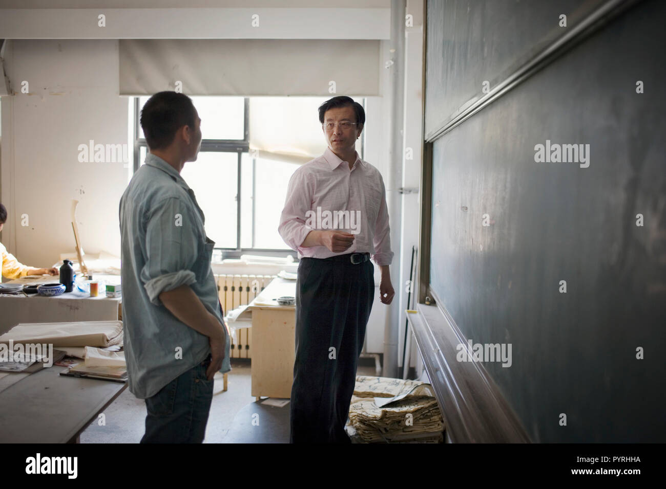 Mid-adult male teacher and young adult man in a classroom Stock Photo ...