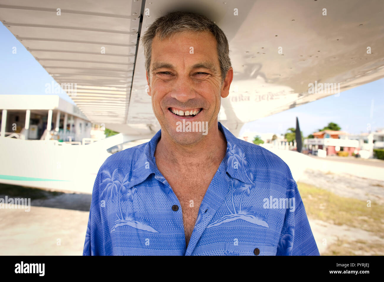 Portrait of a grinning mature man standing underneath the wing of an ...