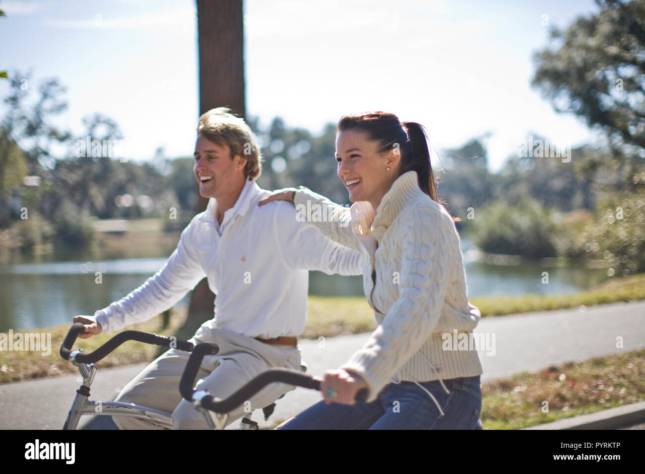 Couple holding onto each other as they ride bikes Stock Photo - Alamy