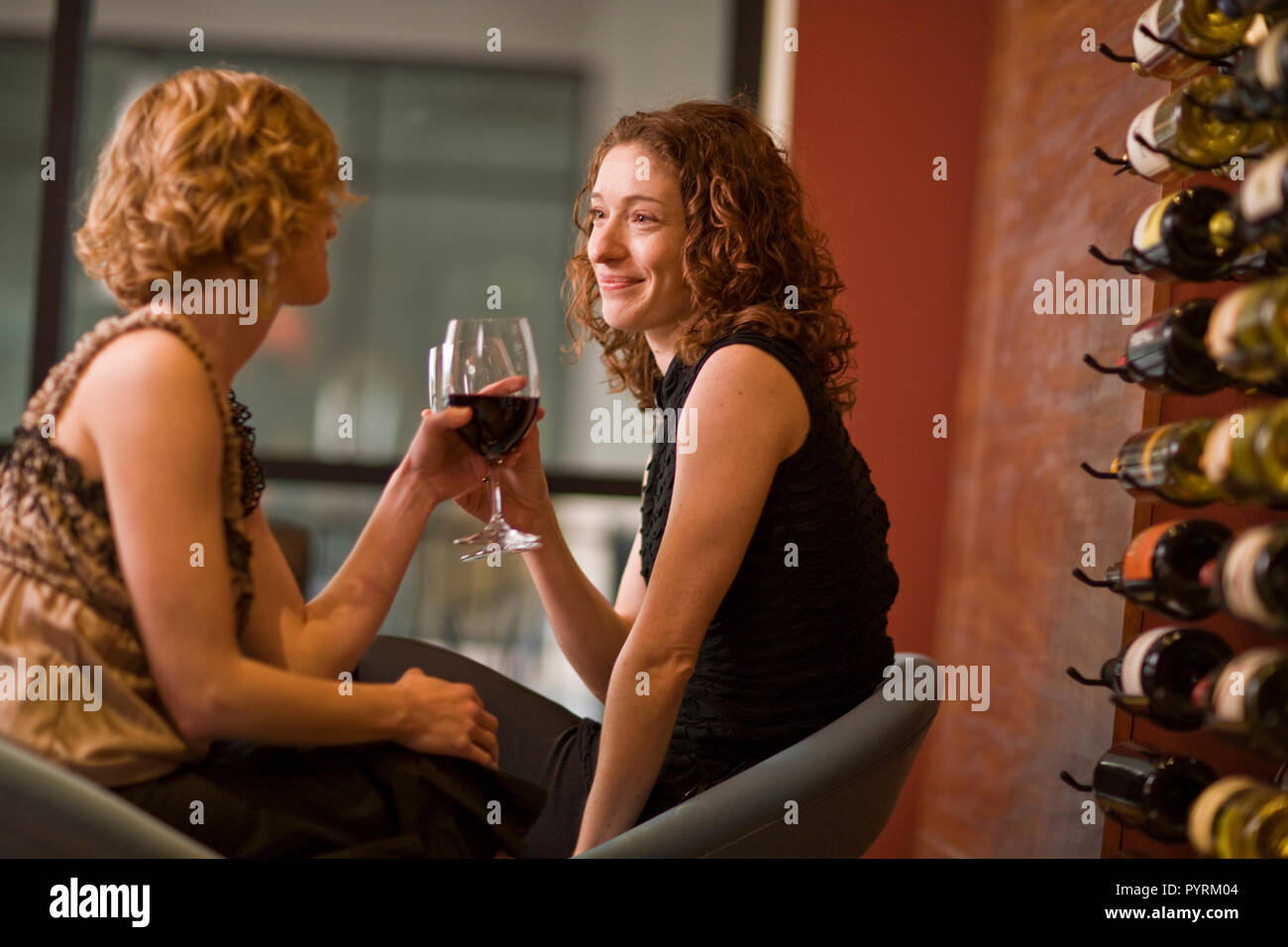 Two women drinking wine together and smiling Stock Photo - Alamy