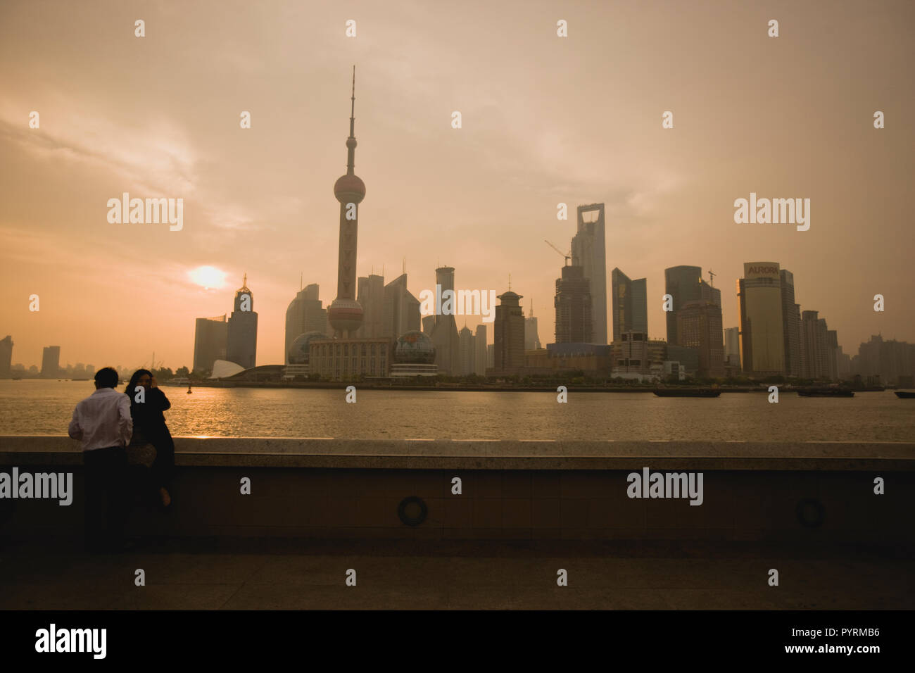 Couple standing on a viewing platform overlooking a harbor and skyline ...