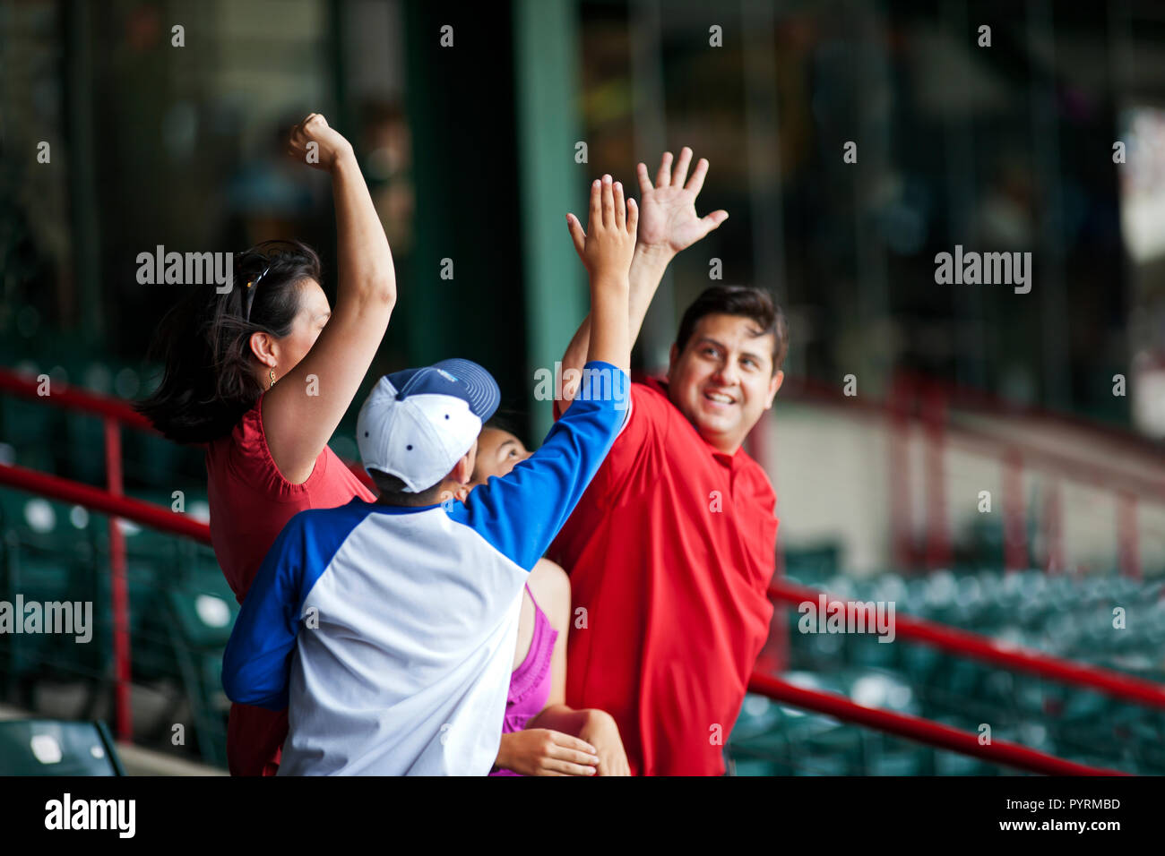 Smiling father and son high fiving each other at a baseball game Stock ...