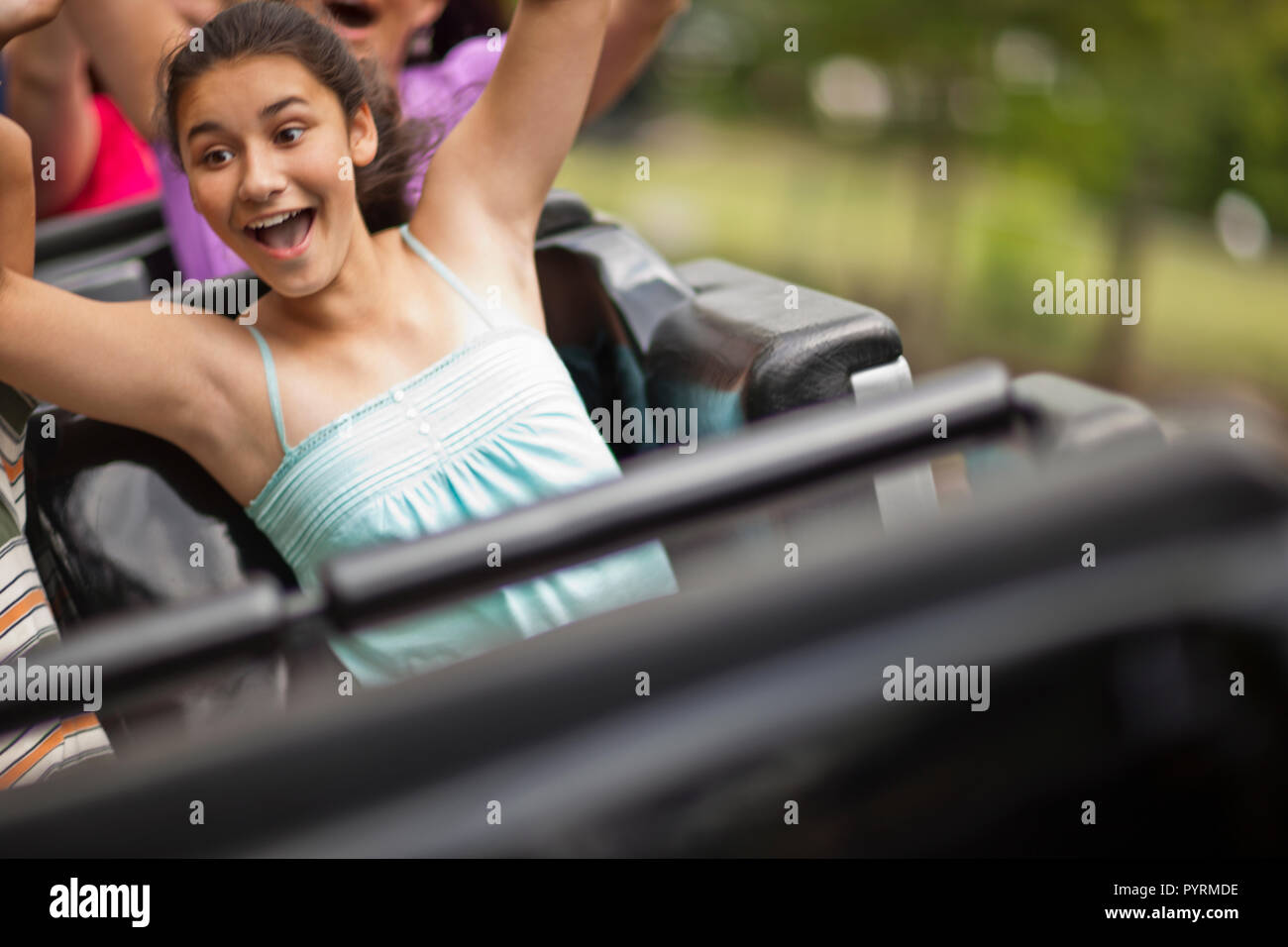 Happy people riding a rollercoaster at an amusement park Stock Photo ...
