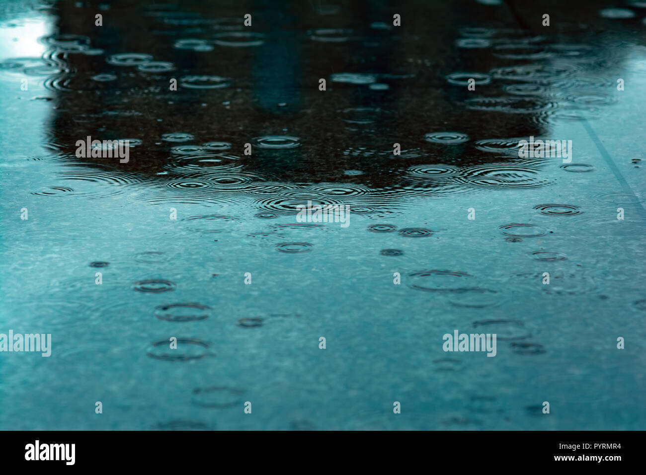 Splashes and raindrops in a puddle Stock Photo - Alamy