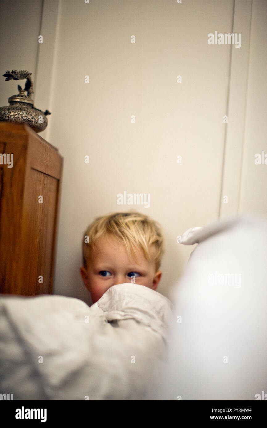 Little boy hiding next to bed Stock Photo - Alamy