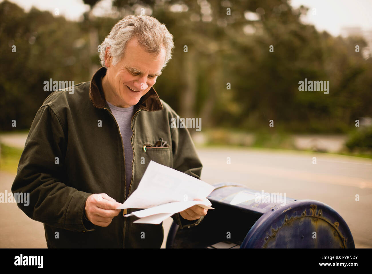 Man standing next to post box reading letter Stock Photo - Alamy