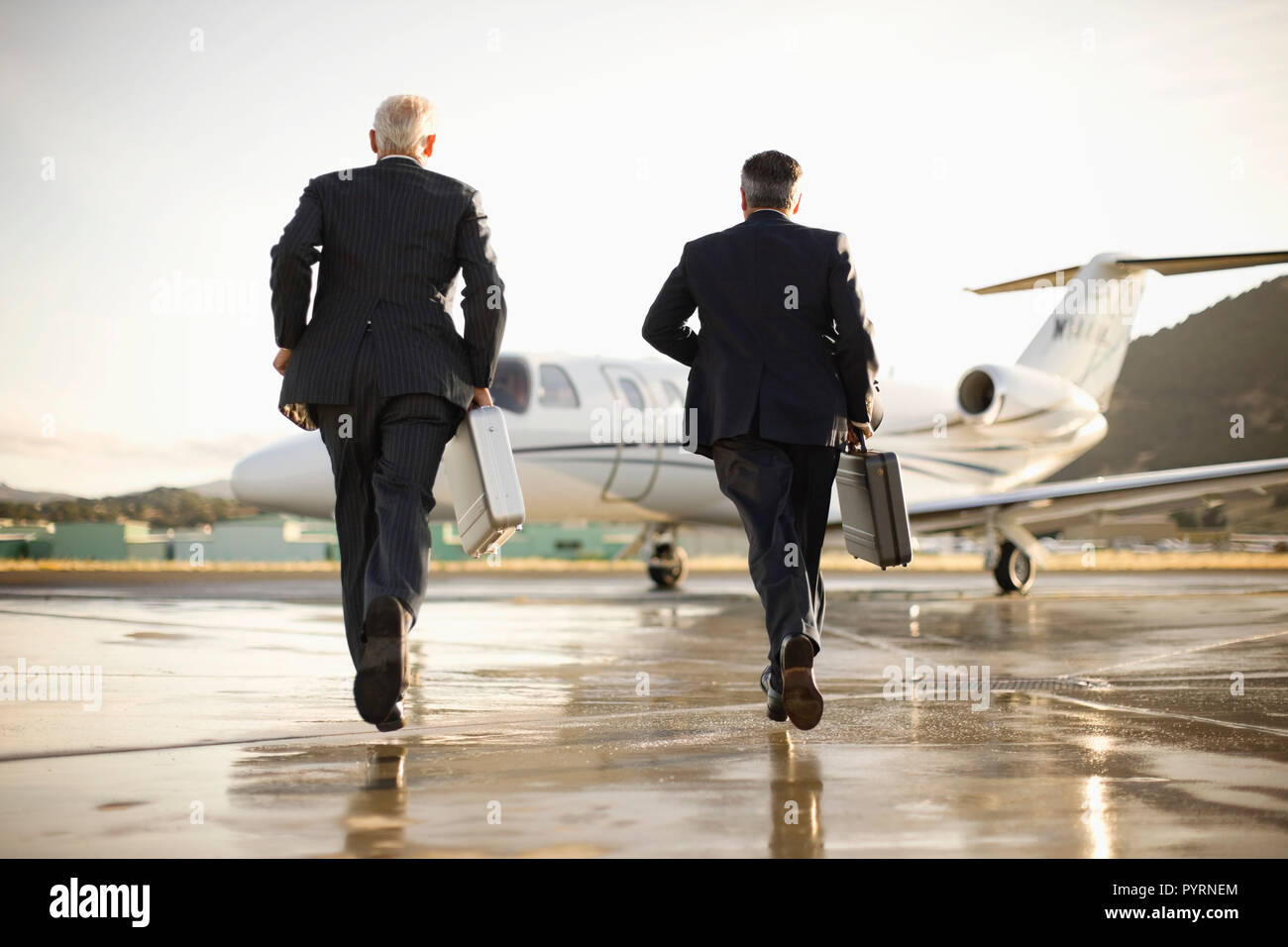 Two businessmen running towards a private jet Stock Photo - Alamy