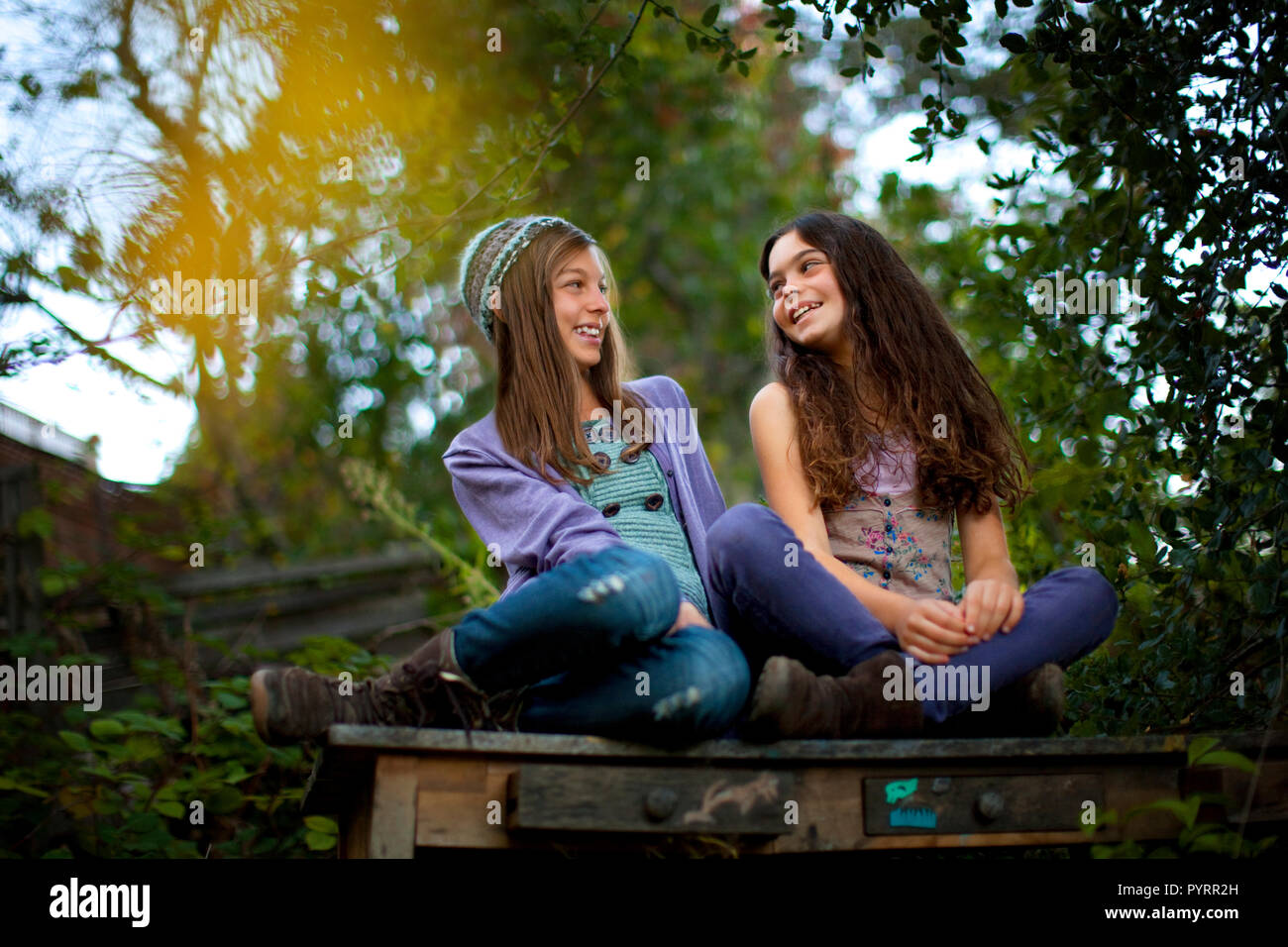 Two friends sitting on a worn desk Stock Photo - Alamy