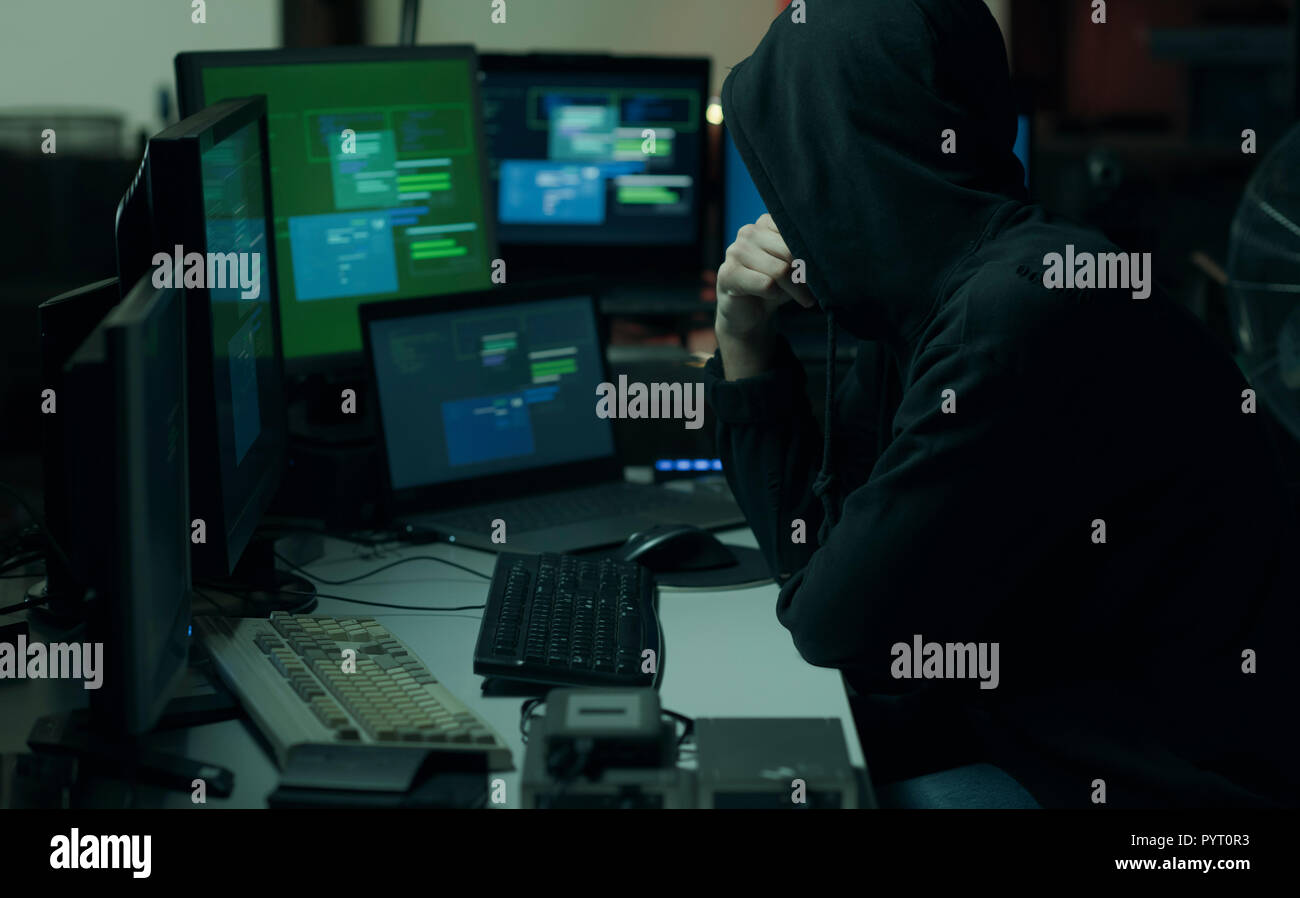 Cool young hacker with hoodie working with computers, cybercrime and ...