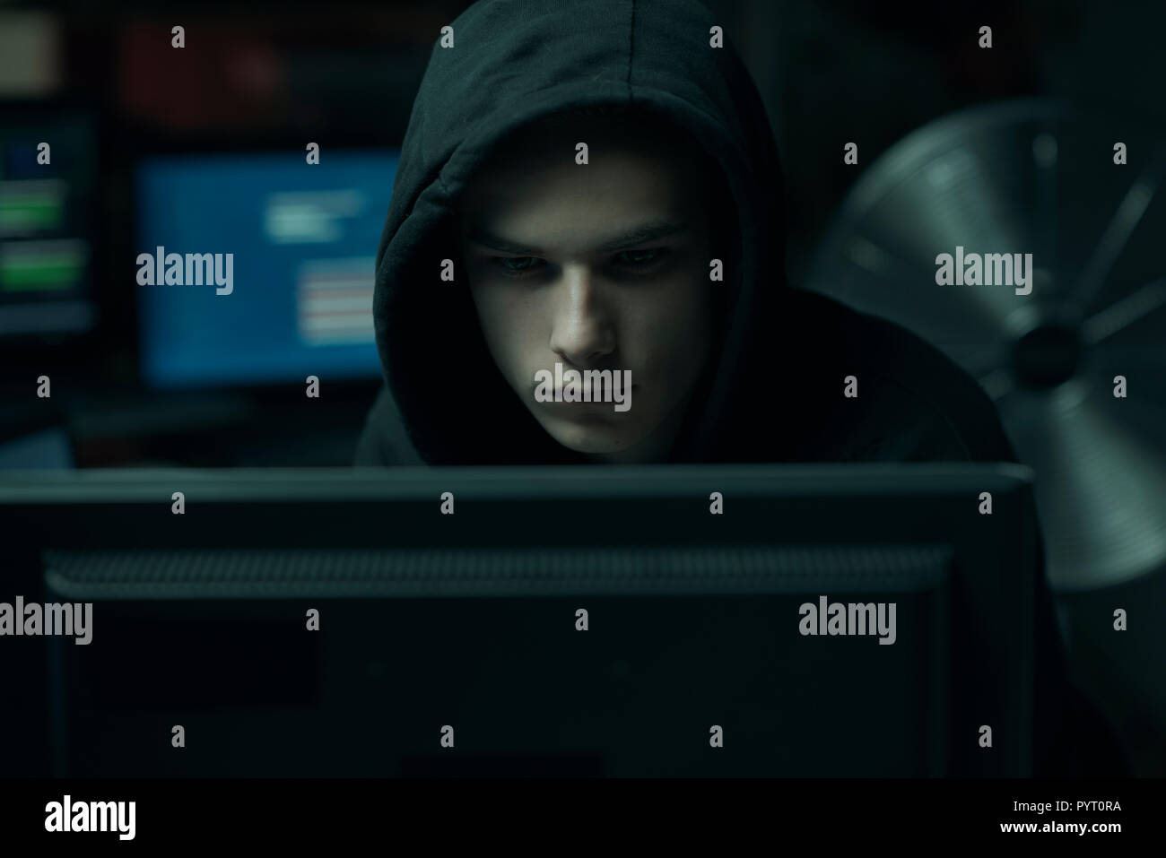 Cool young hacker with hoodie working with computers, cybercrime and ...